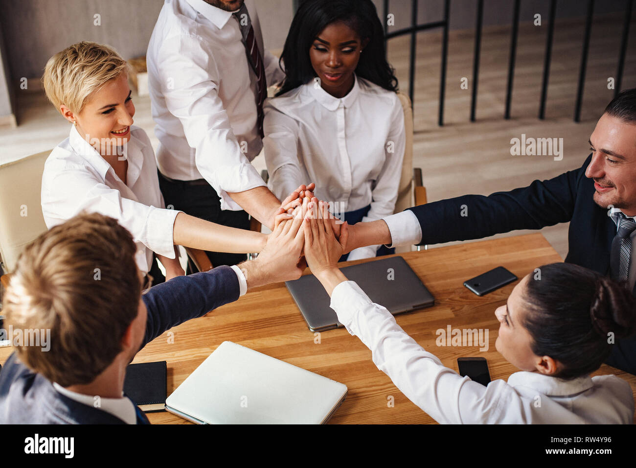Business Group Sitting Around Desk In Office And Giving Five After ...