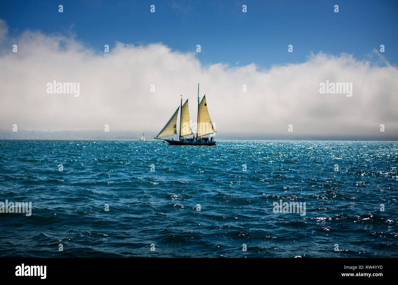 View across sea to sailing ship Stock Photo - Alamy