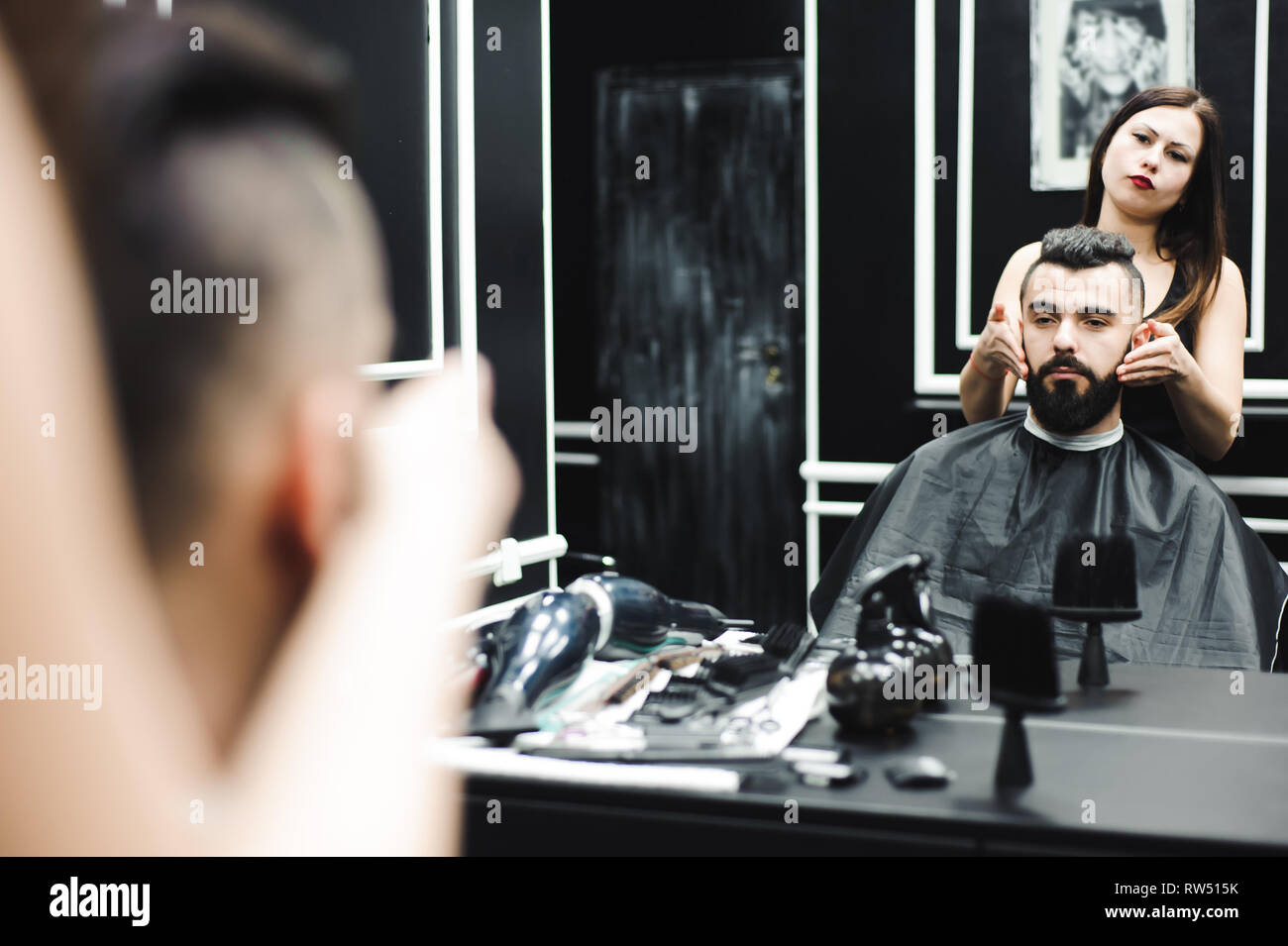Master cuts hair and beard of men in the barbershop, hairdresser makes ...