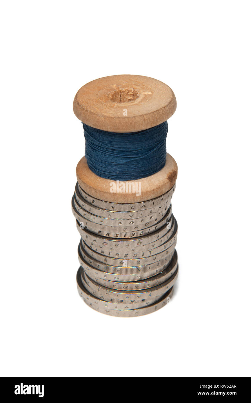 Rows of coins isolated on white background next to multicolored thread ...