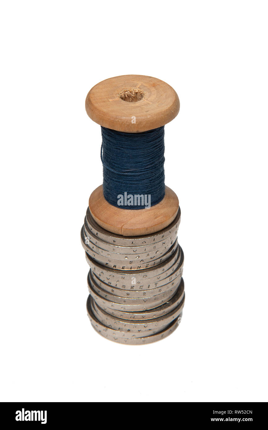 Rows of coins isolated on white background next to multicolored thread ...