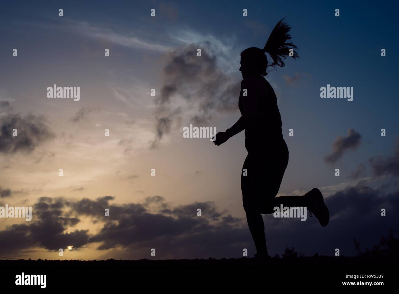 Jumping Woman and sky with clouds at sunset Stock Photo - Alamy