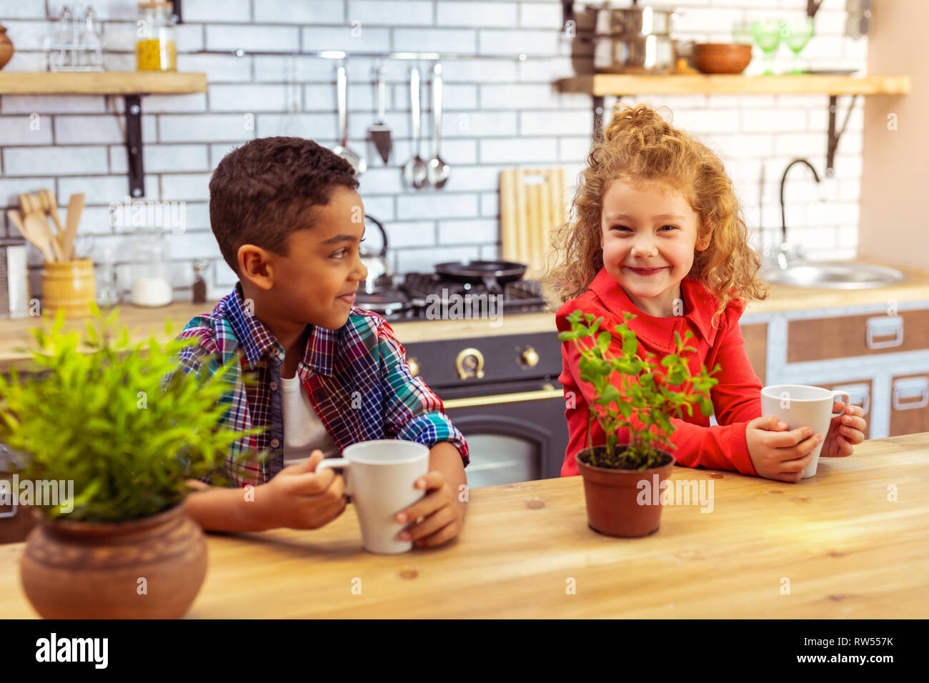 Kind brunette boy sitting near his pretty friend Stock Photo - Alamy