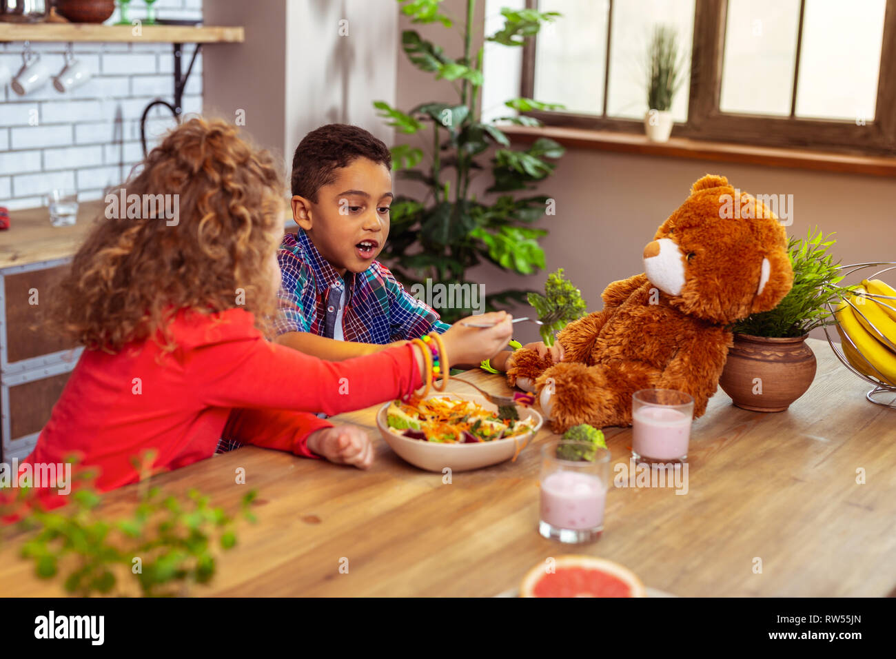 Joyful kids playing together with teddy bear Stock Photo - Alamy