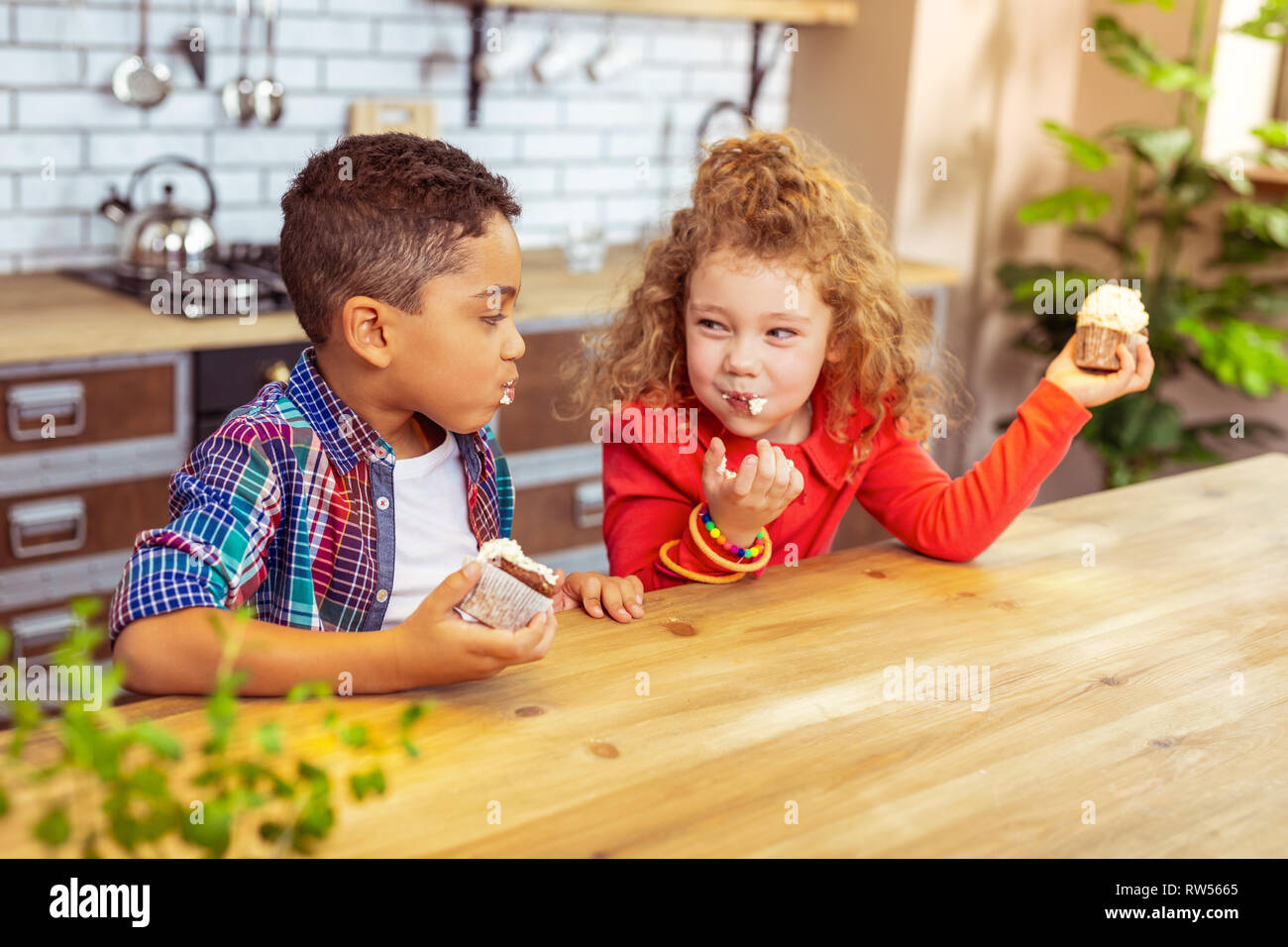 Positive delighted kids talking while eating desserts Stock Photo - Alamy