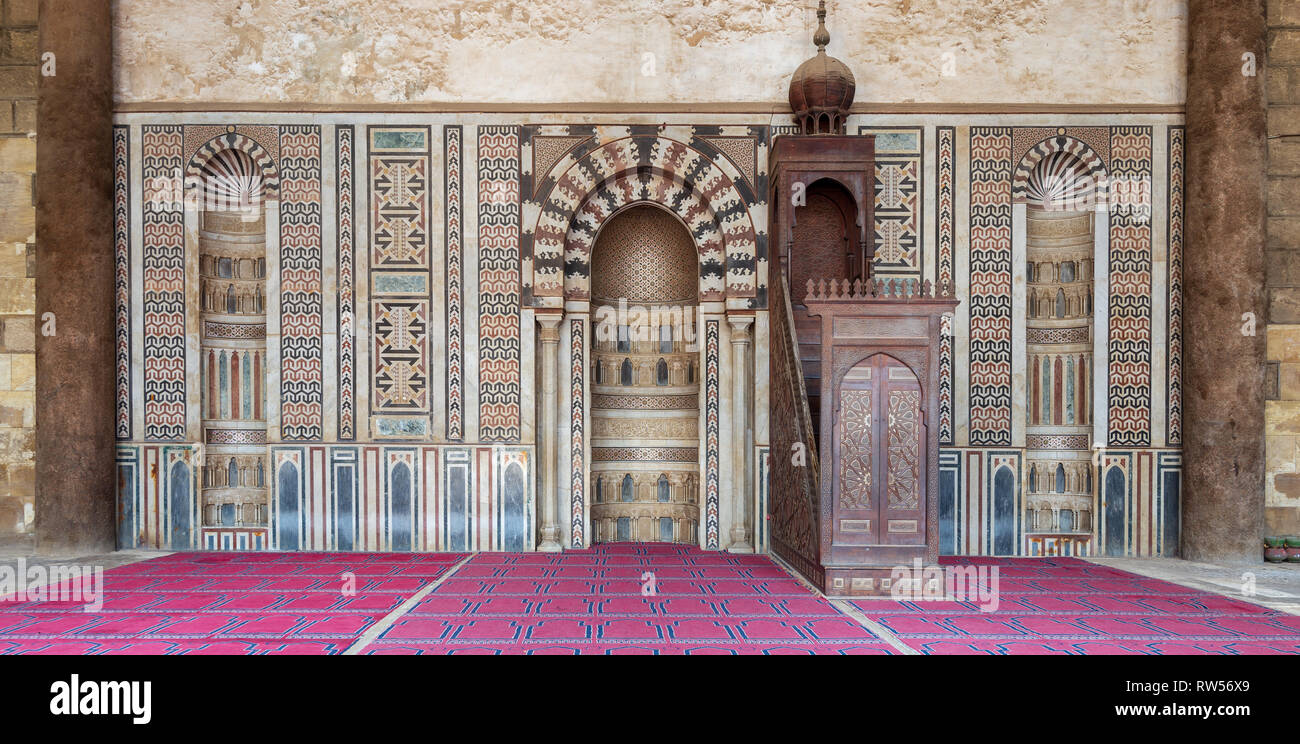 Colorful decorated marble wall with engraved Mihrab (niche) and wooden ...
