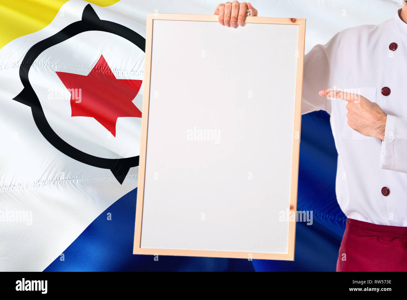Chef holding blank whiteboard menu on Bonaire flag background. Cook ...