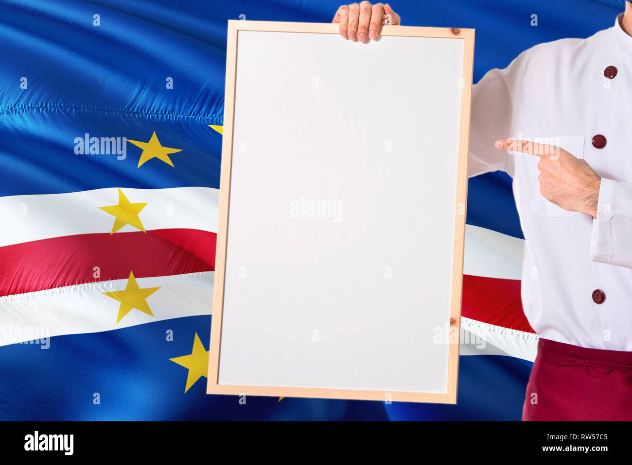 Chef holding blank whiteboard menu on Cape Verde flag background. Cook ...