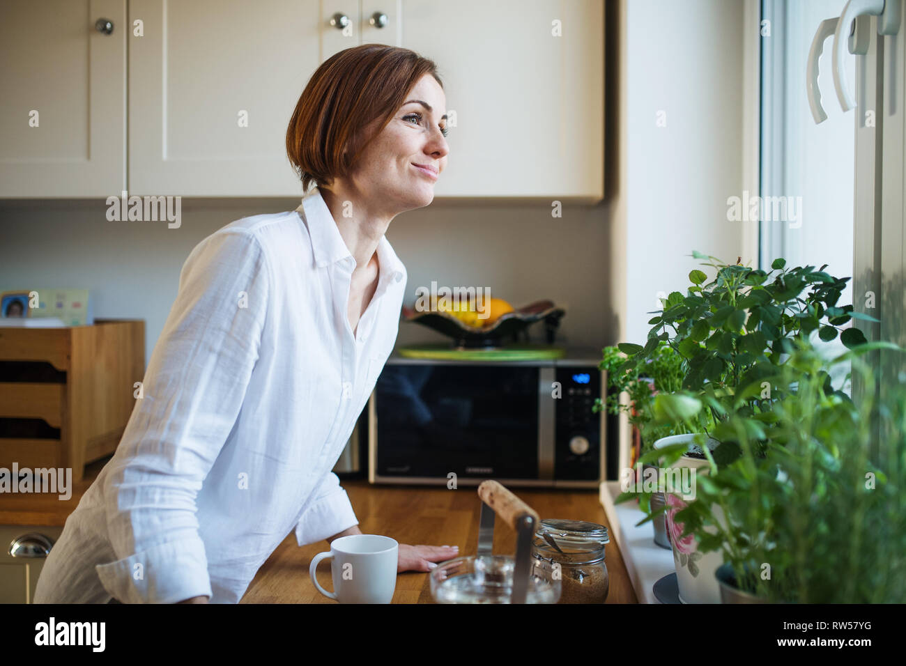 A young woman looking out of a window in the kitchen Stock Photo - Alamy