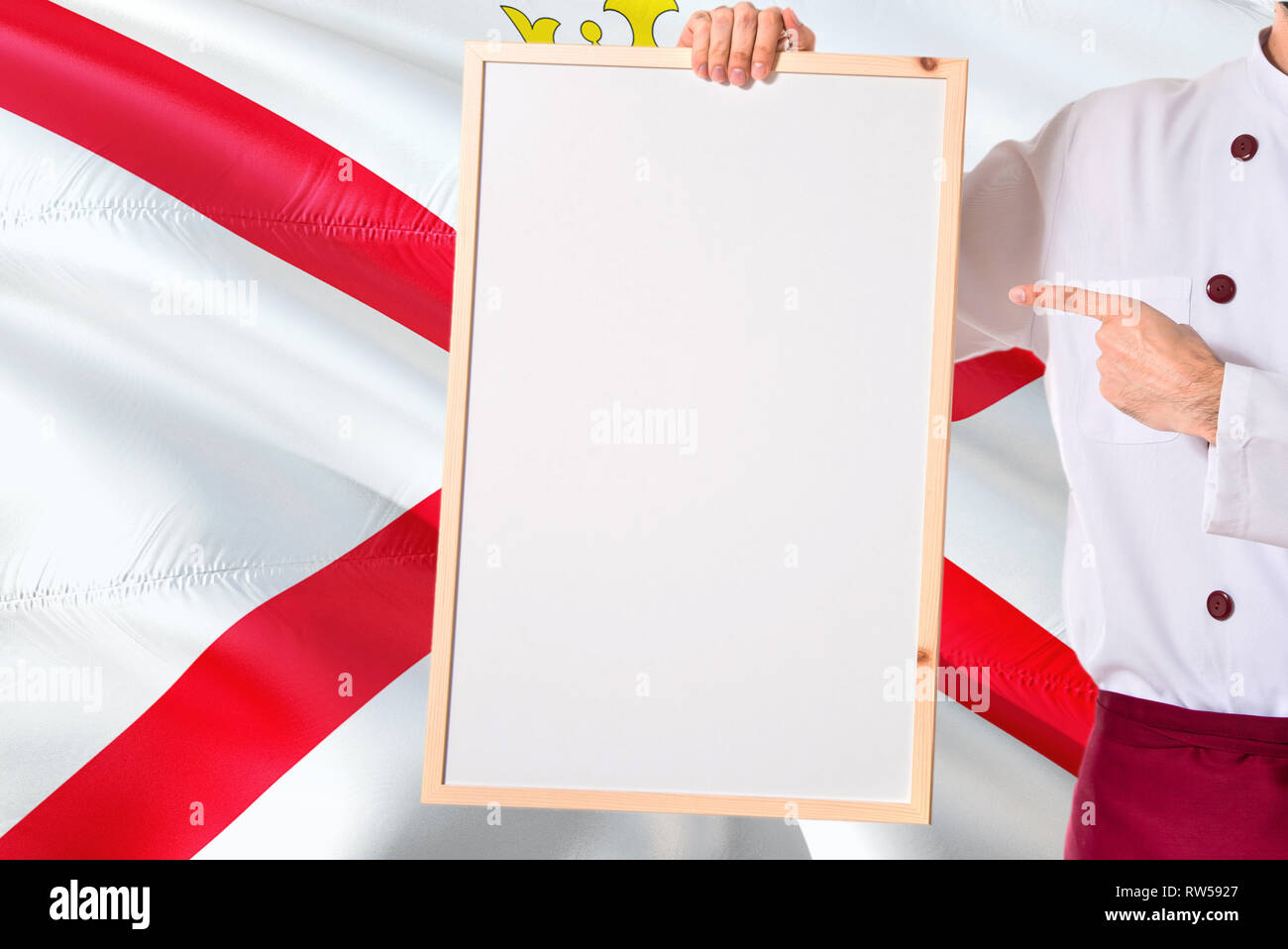 Chef holding blank whiteboard menu on Jersey flag background. Cook ...