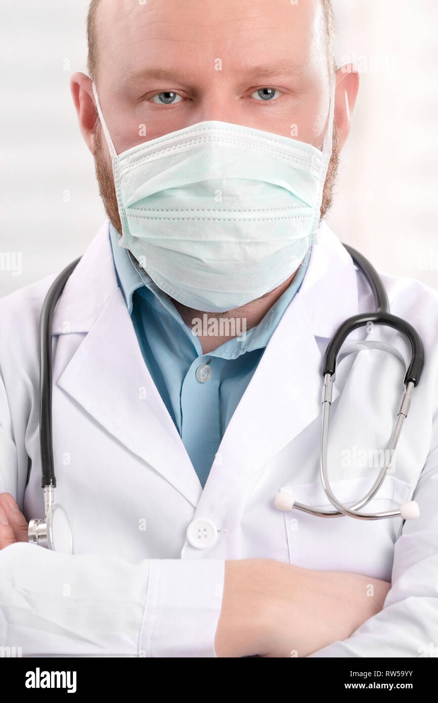 Portrait of a serious doctor wearing surgical face mask and stethoscope ...