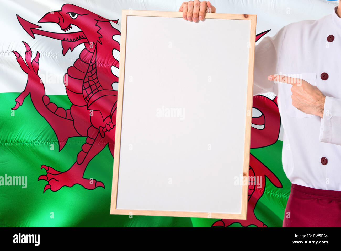 Welsh Chef holding blank whiteboard menu on Wales flag background. Cook ...
