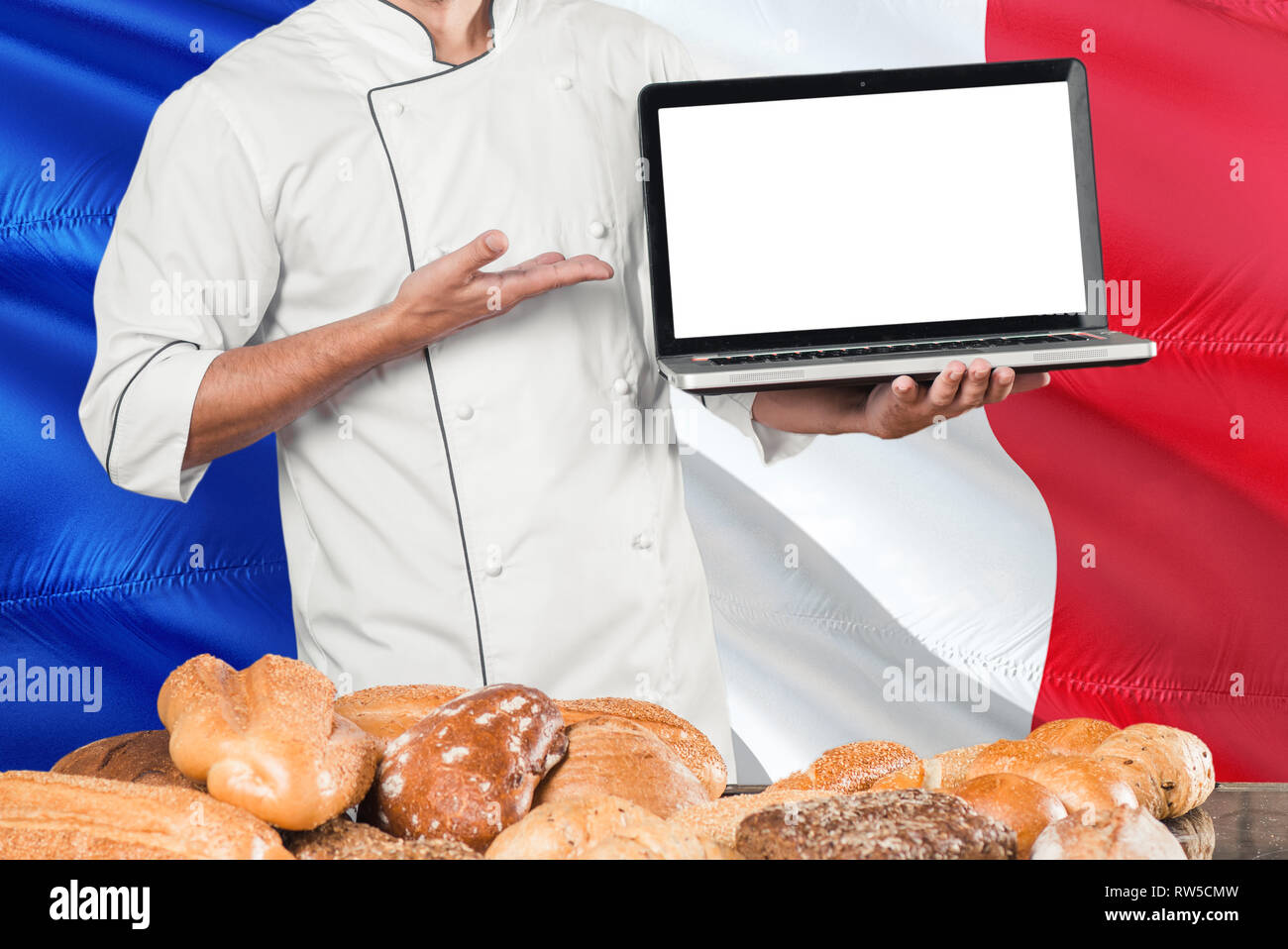French Baker holding laptop on France flag and breads background. Chef ...