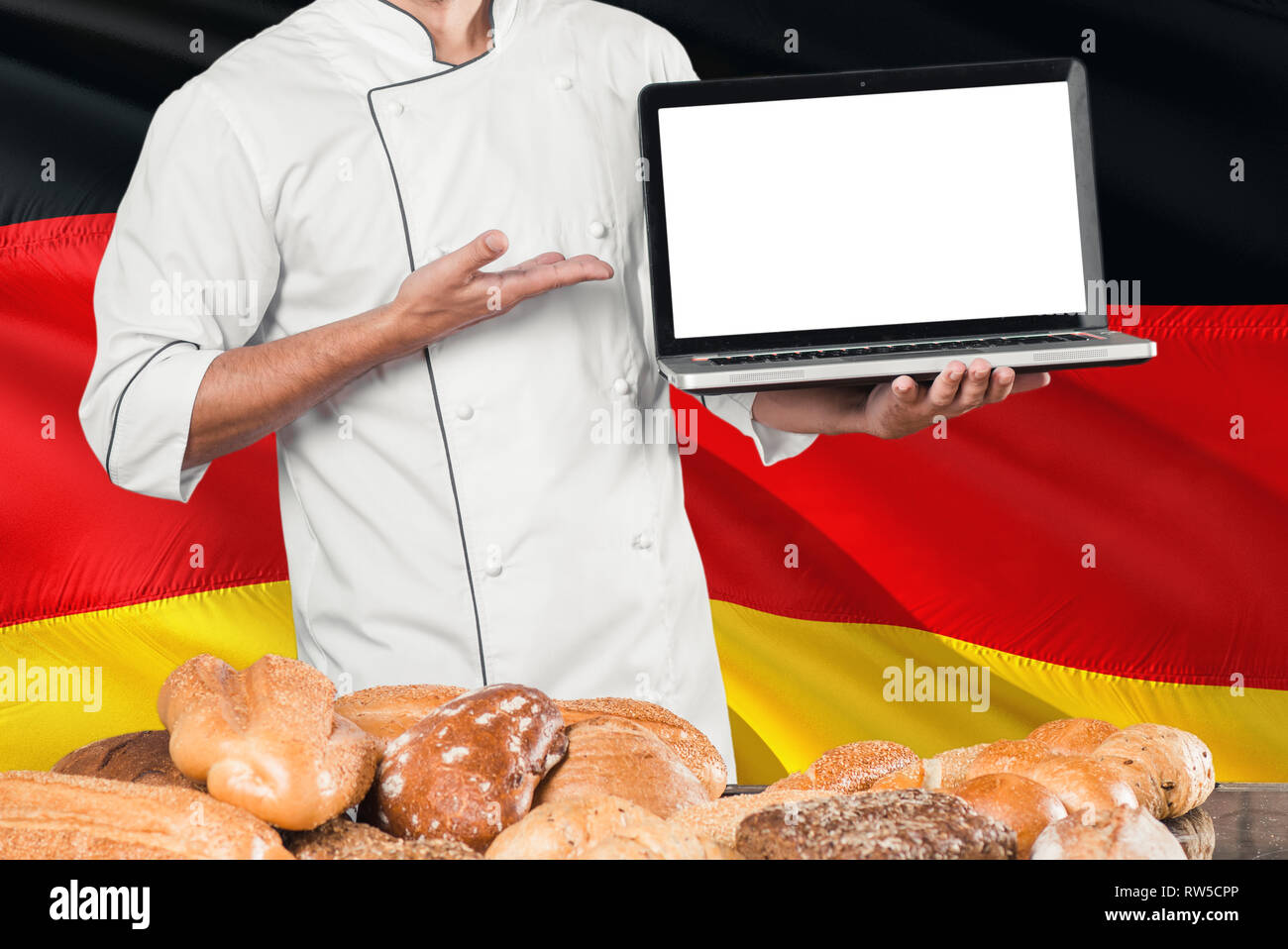 German Baker holding laptop on Germany flag and breads background. Chef ...