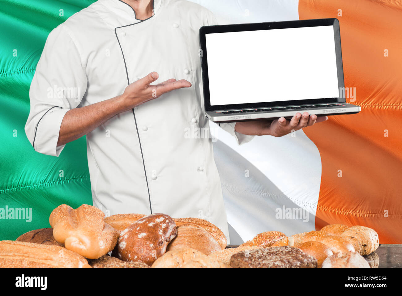 Irish Baker holding laptop on Ireland flag and breads background. Chef ...