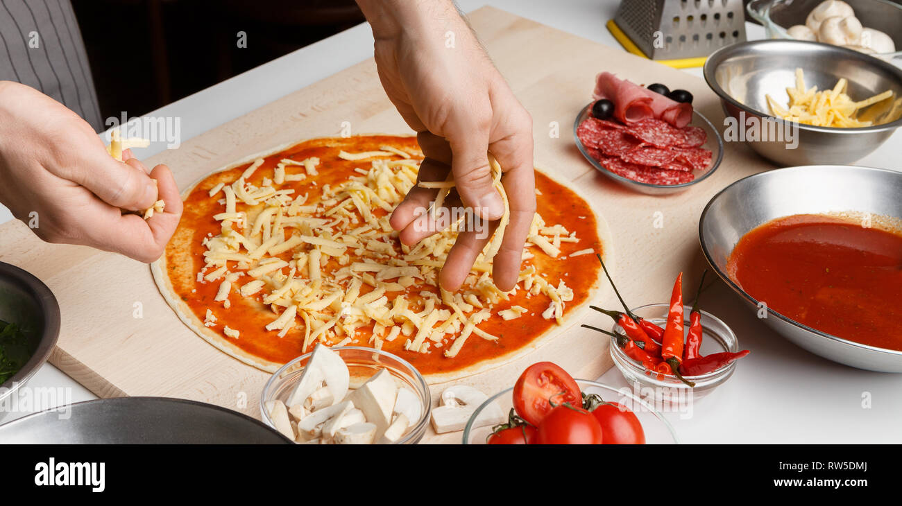 Chef sprinkling pizza with cheese at kitchen Stock Photo - Alamy