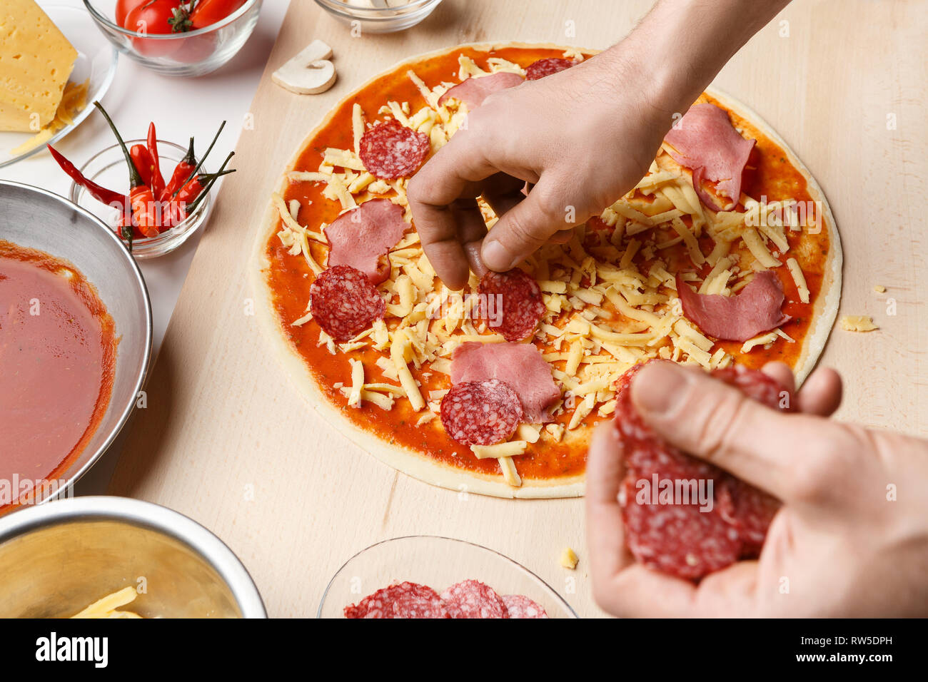 Chef cooking salami pizza, adding ingredients on it Stock Photo - Alamy