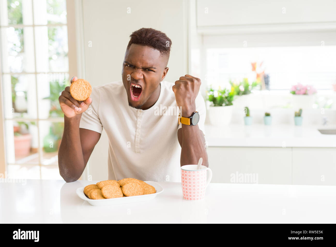 African american man eating healthy whole grain biscuit annoyed and ...