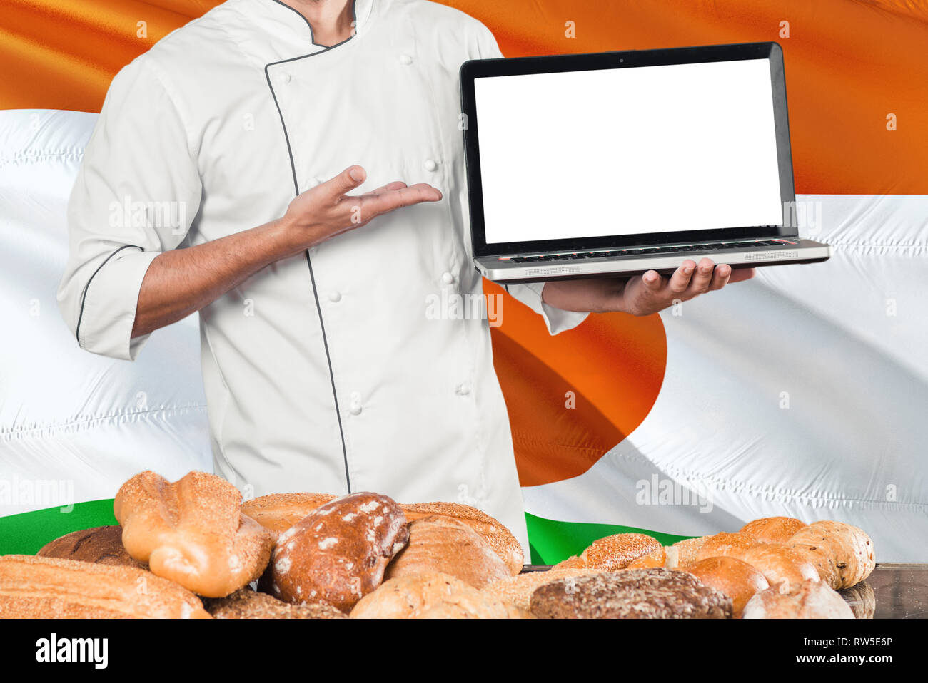 Nigerian Baker holding laptop on Nigeria flag and breads background ...