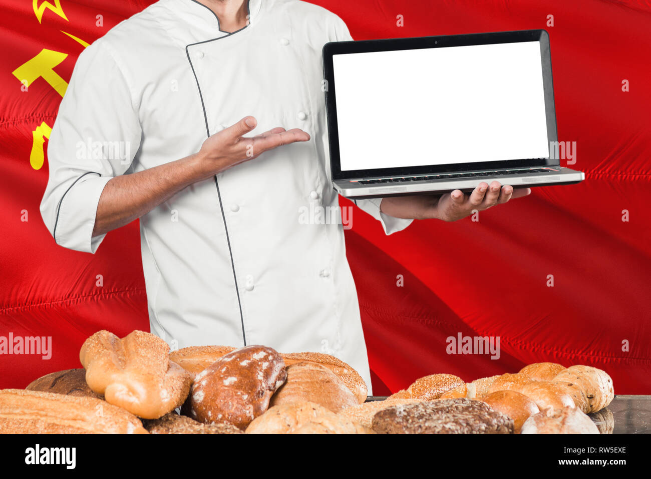 Baker holding laptop on Soviet Union flag and breads background. Chef ...