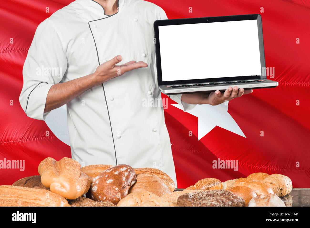 Turkish Baker holding laptop on Turkey flag and breads background. Chef ...