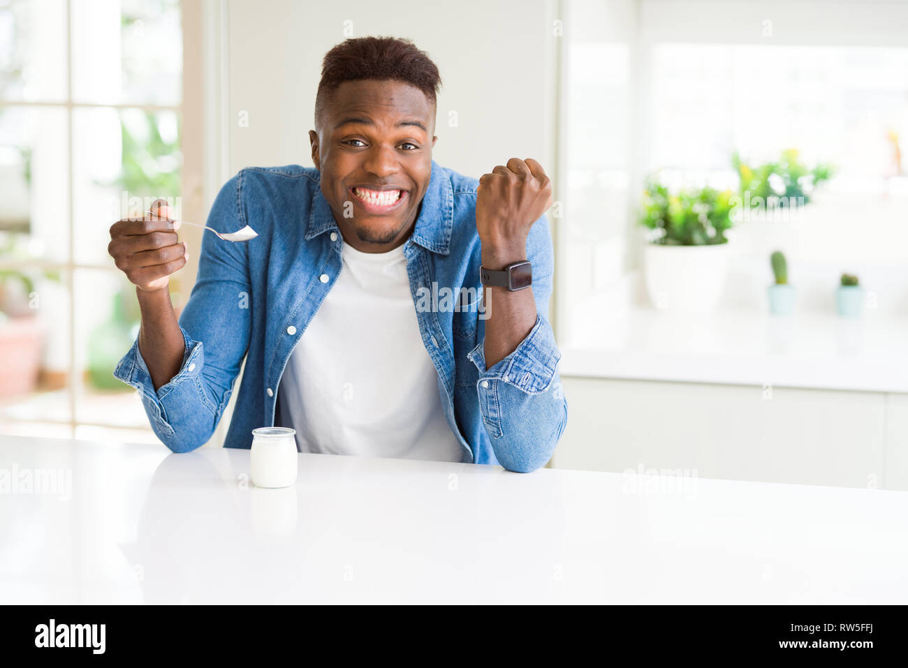 African american man eating healthy natural yogurt with a spoon ...
