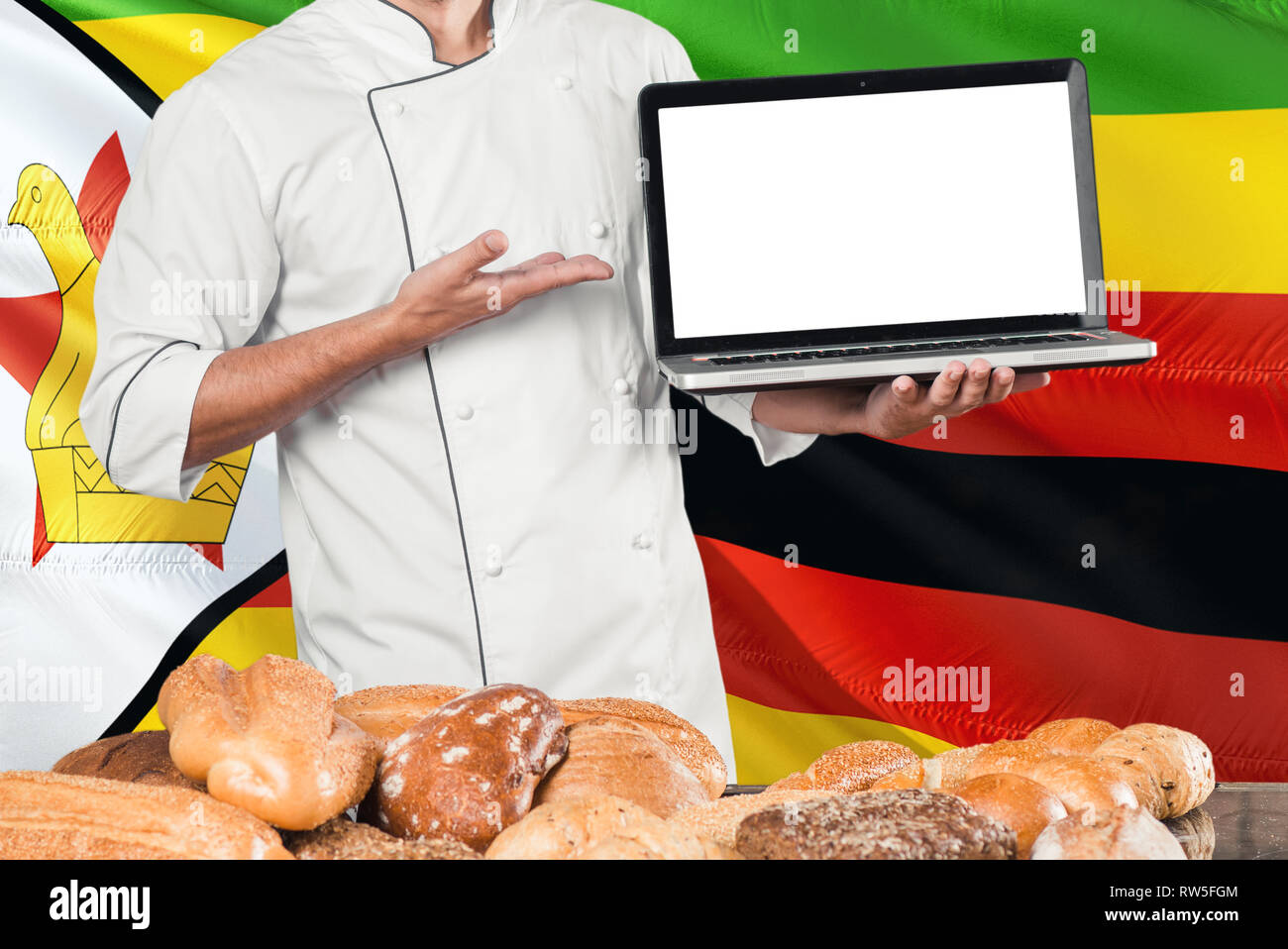 Zimbabwean Baker holding laptop on Zimbabwe flag and breads background ...
