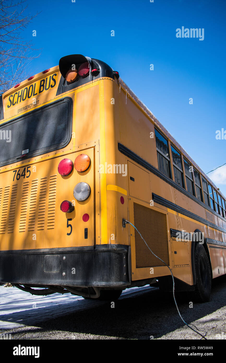 Low angle view of a US school bus in winter with block heater plugged ...