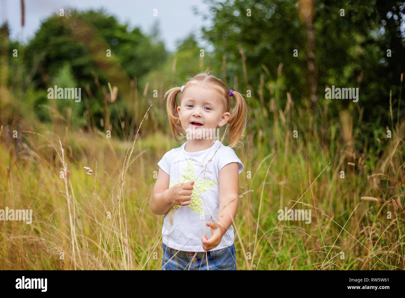 Portrait of happy cute little girl outdoor. Kid palying in park, garden ...