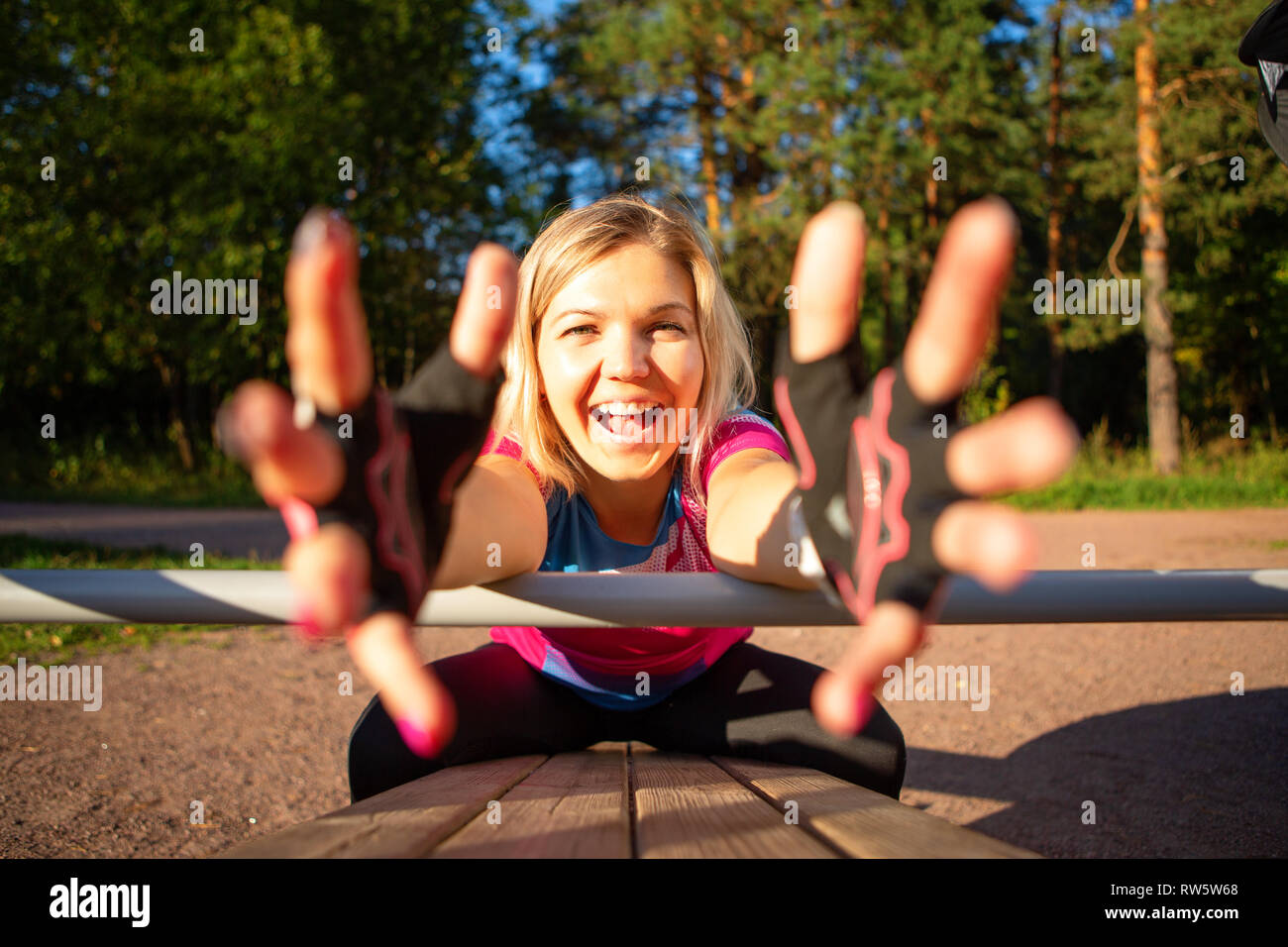 Athlete girl pulling hands forward is exercising at wooden bench in ...
