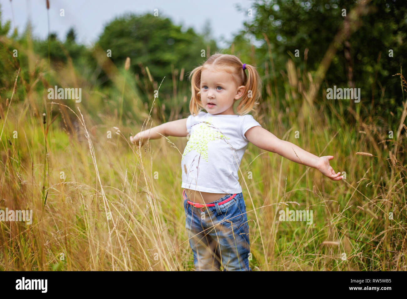 Portrait of happy cute little girl outdoor. Kid palying in park, garden ...