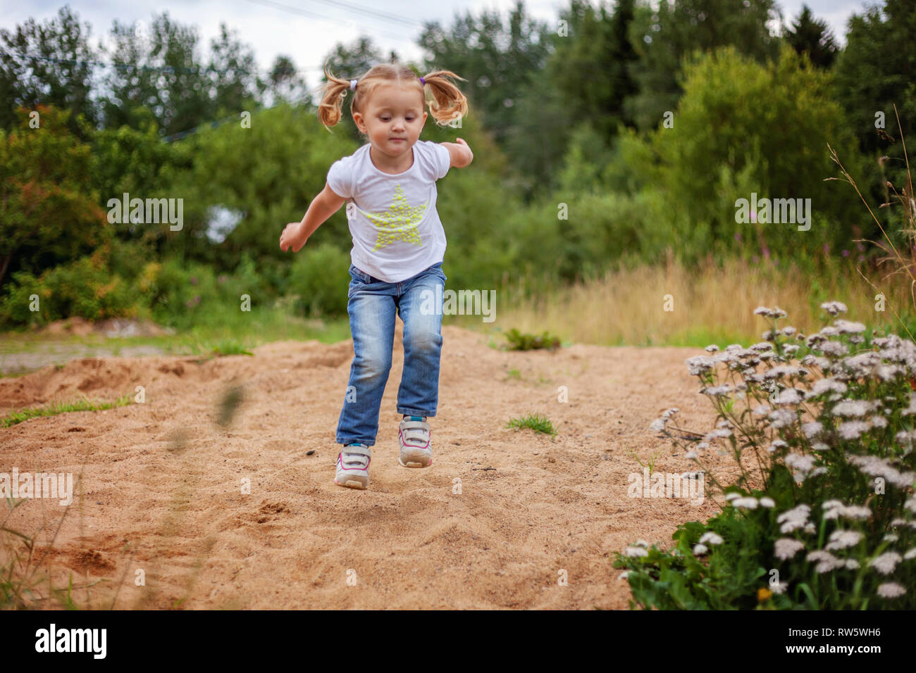 Portrait of happy cute little girl outdoor. Kid palying jumping in park ...