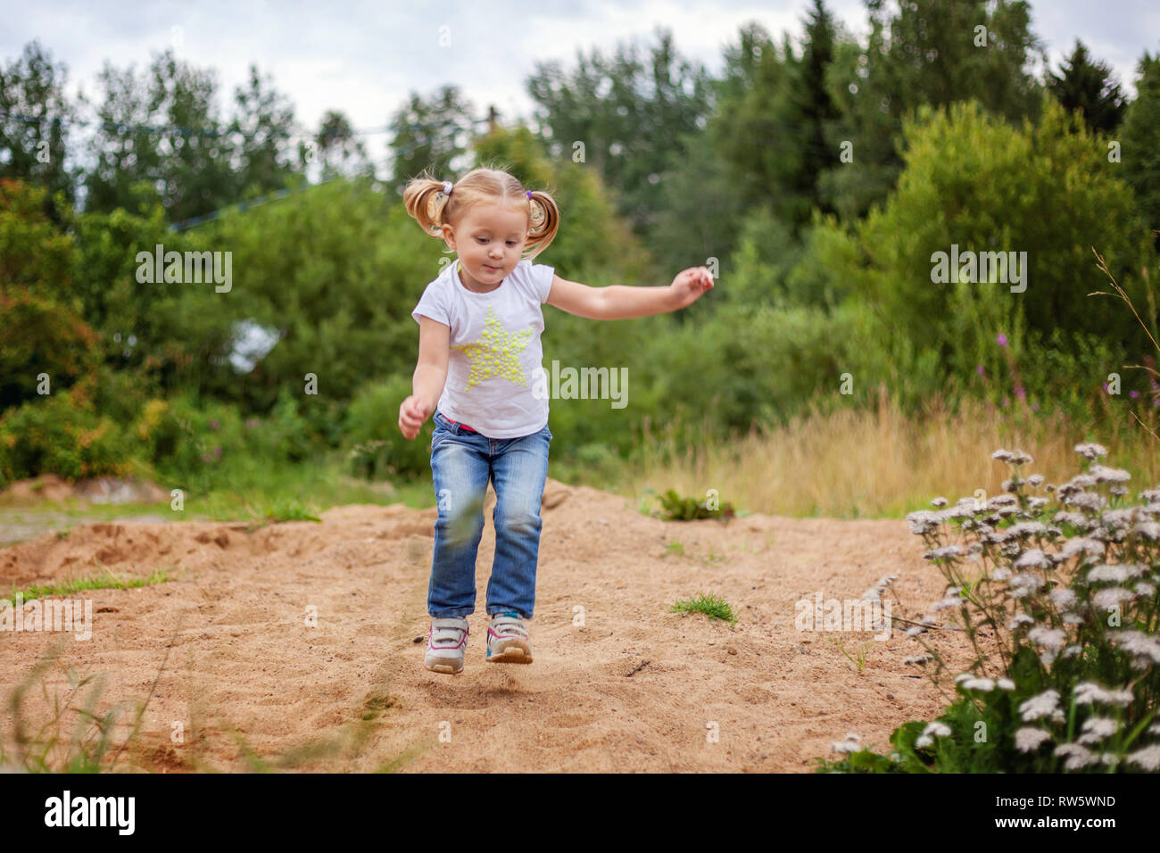 Portrait of happy cute little girl outdoor. Kid palying jumping in park ...