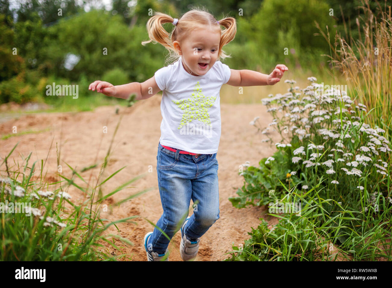 Portrait of happy cute little girl outdoor. Kid palying jumping in park ...