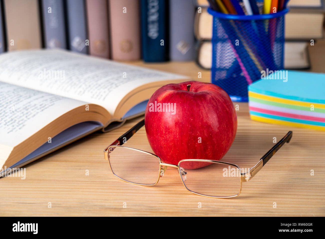 Back to school. Books, red apple, pencils and glasses on wooden table ...