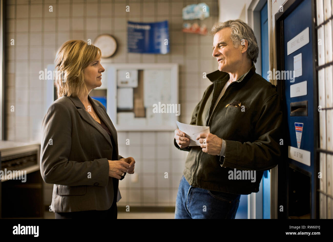 Two acquaintances running into each other in post box room Stock Photo ...