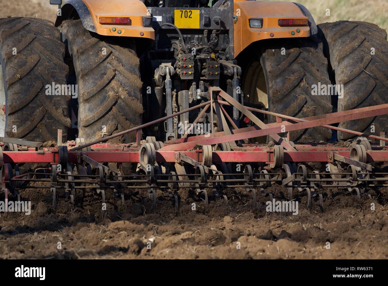 A French farmer operating a tractor with dual wheels and a spring tine ...