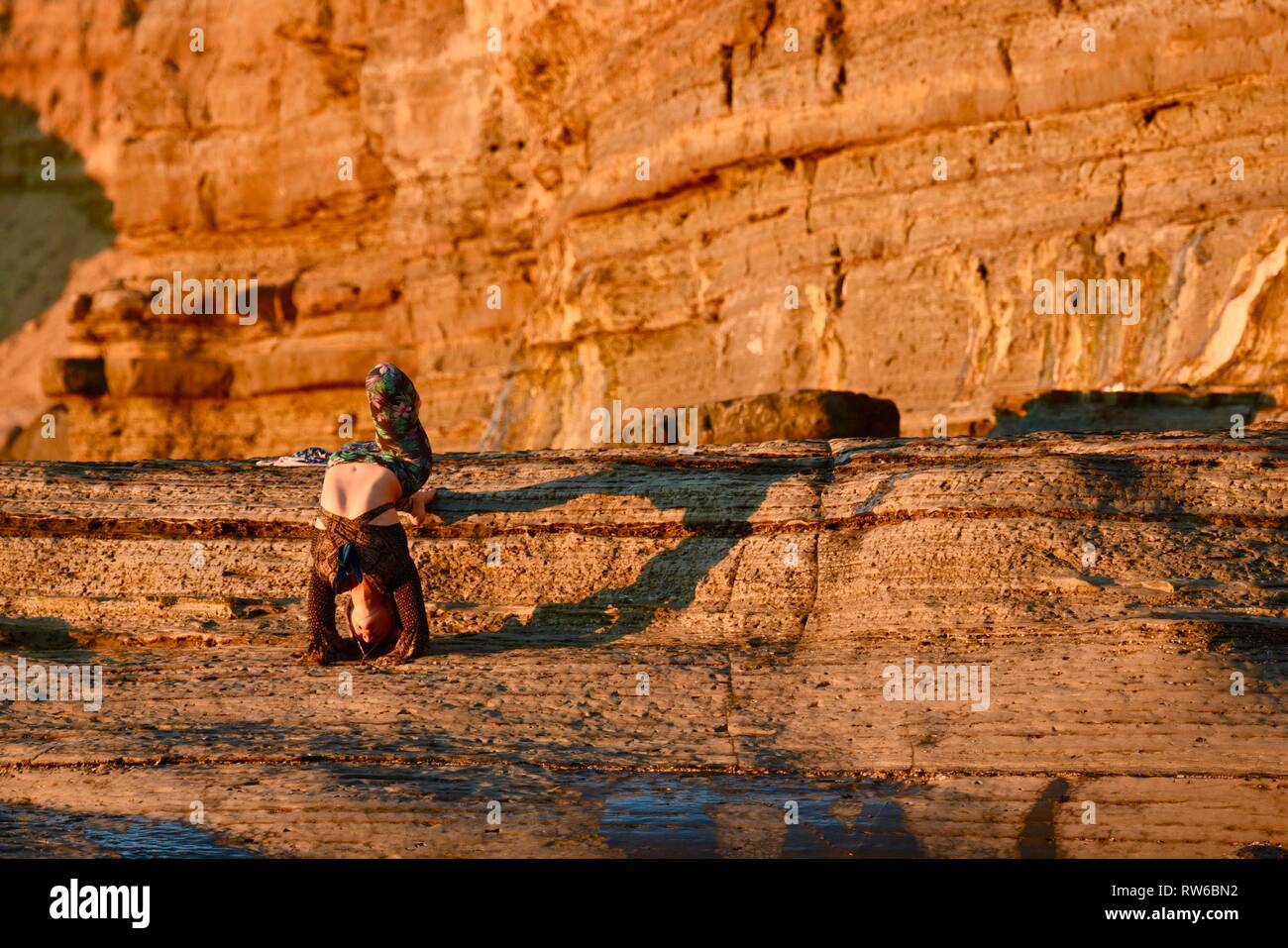 Beautiful young woman upside down in yoga pose throwing shadow on ...