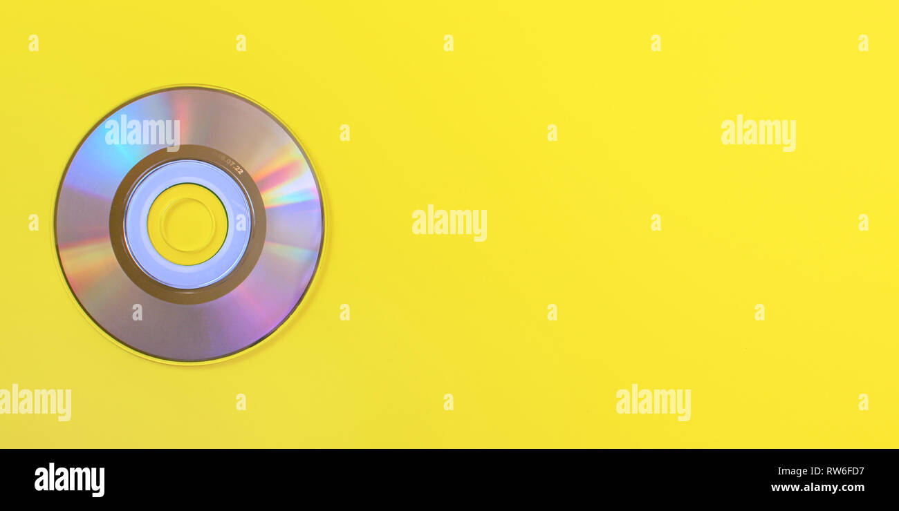 Top down view, small CD shiny / rainbow side, on yellow board, space ...