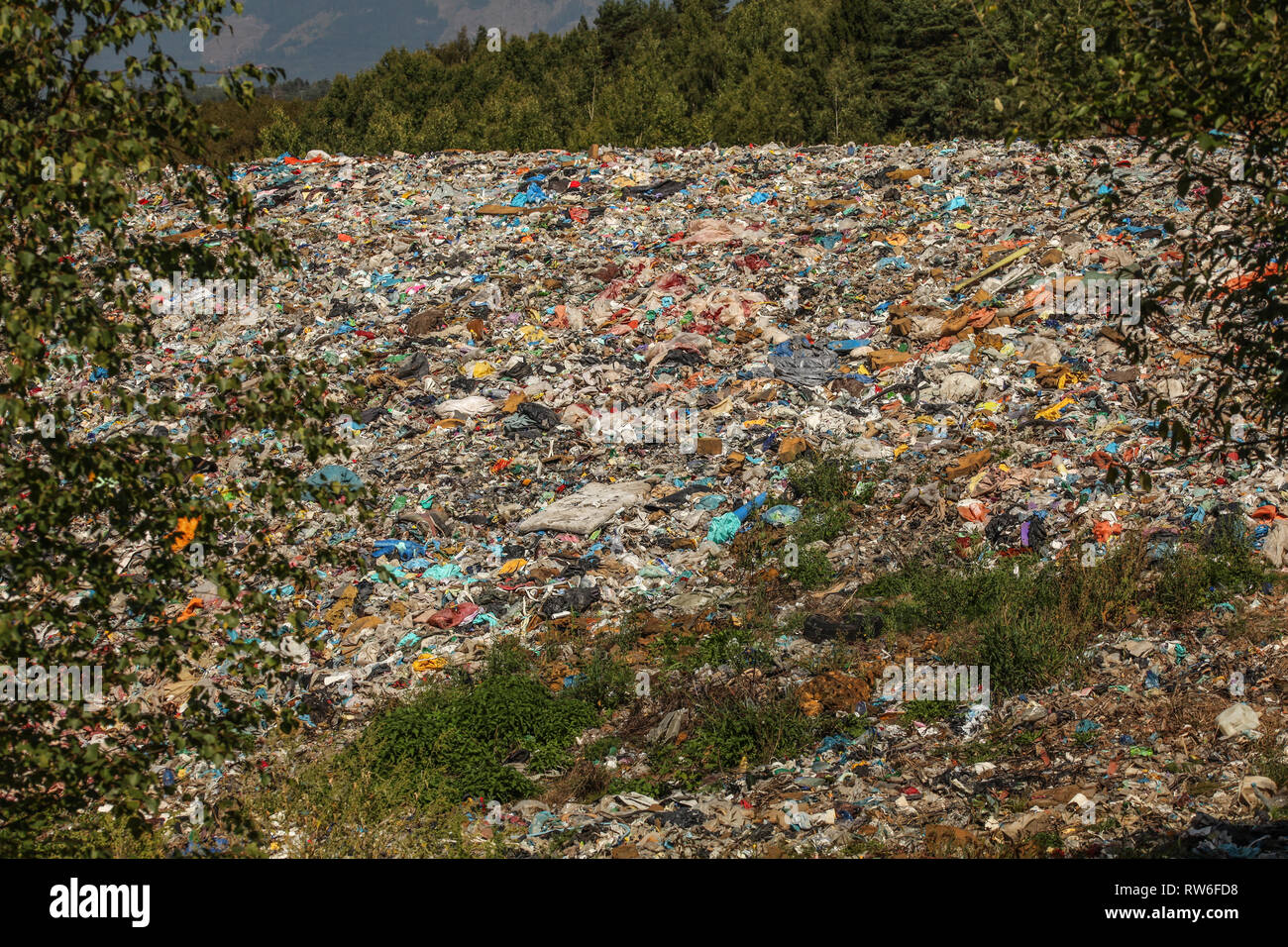 Landfill / dump site surrounded by green trees and mountains in ...