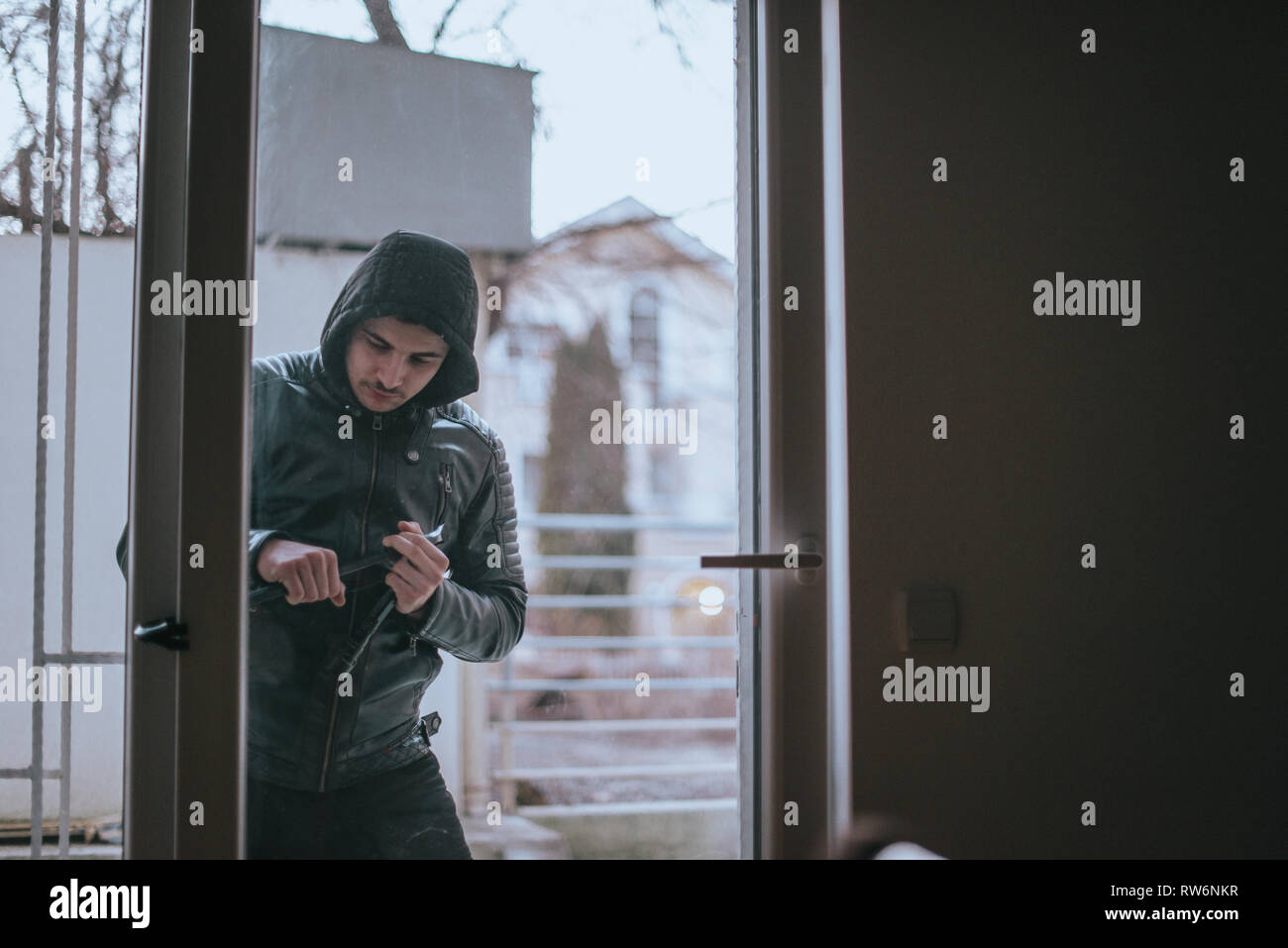 Burglar breaking in to home in day through window Stock Photo - Alamy
