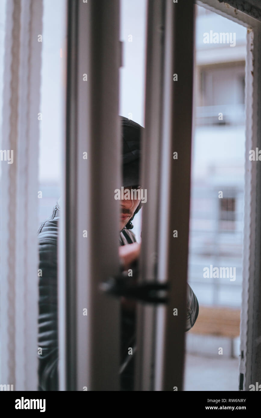 Burglar breaking in to home in day through window Stock Photo - Alamy