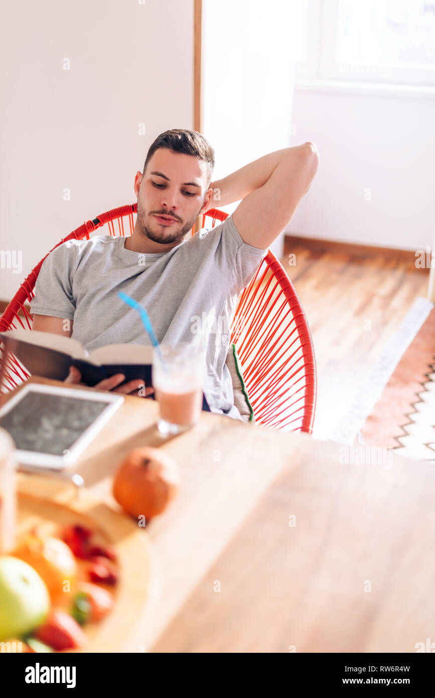 healthy strong young man reading a book early in the morning while ...