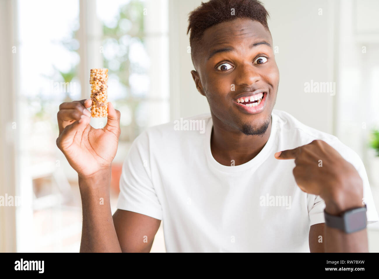 African american man eating energetic cereals bar with surprise face ...