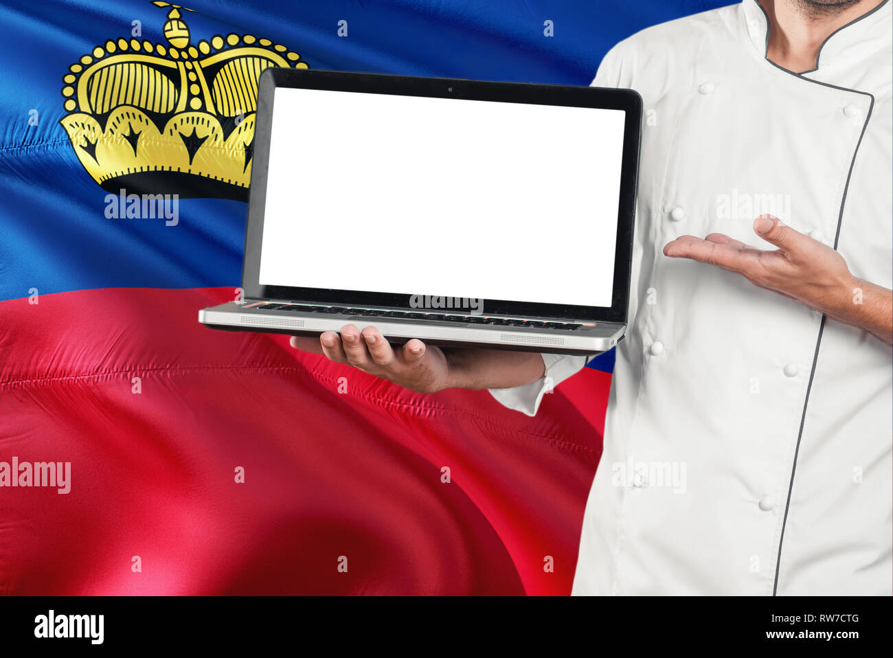 Chef holding laptop with blank screen on Liechtenstein flag background ...
