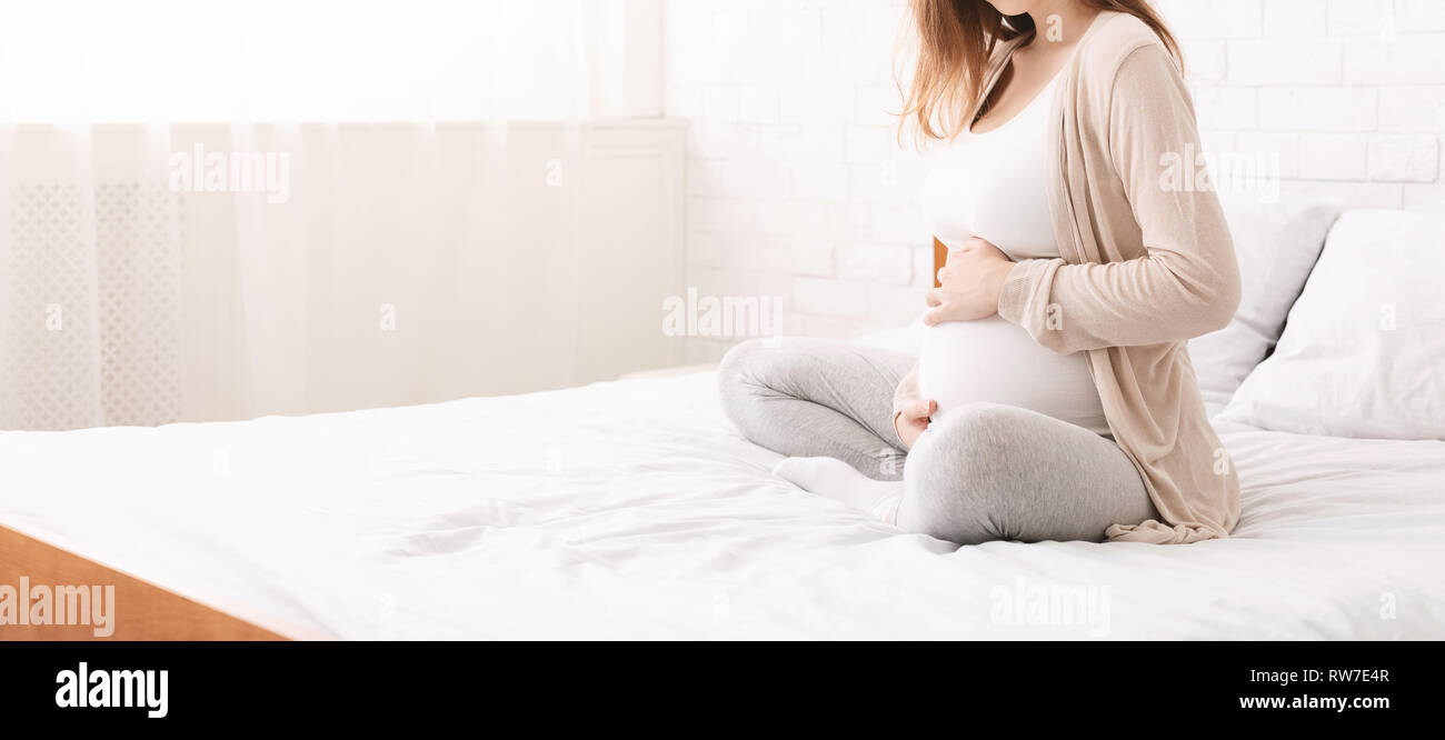 Pregnant happy woman touching her belly in bed Stock Photo - Alamy
