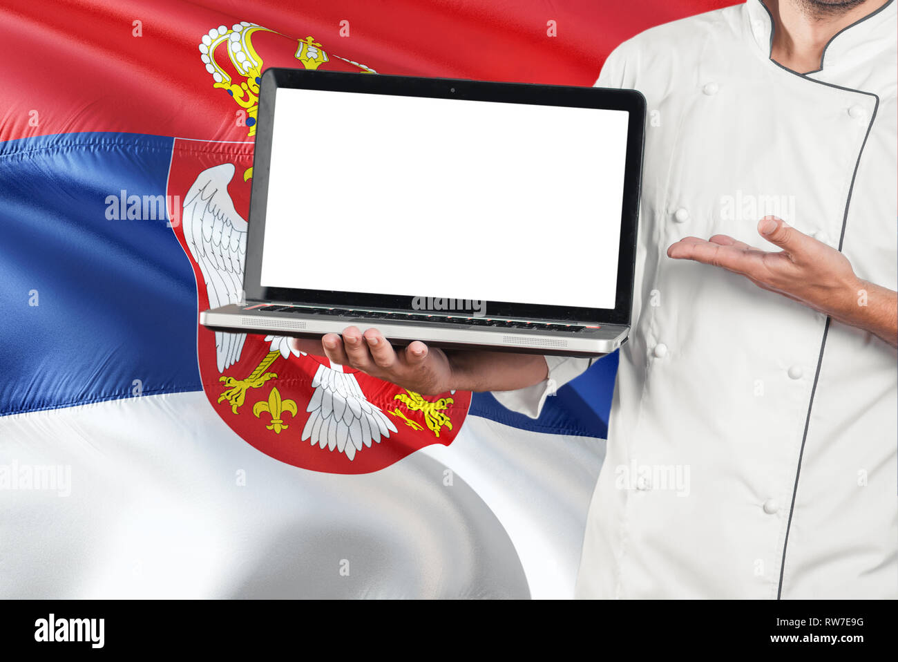 Serbian Chef holding laptop with blank screen on Serbia flag background ...