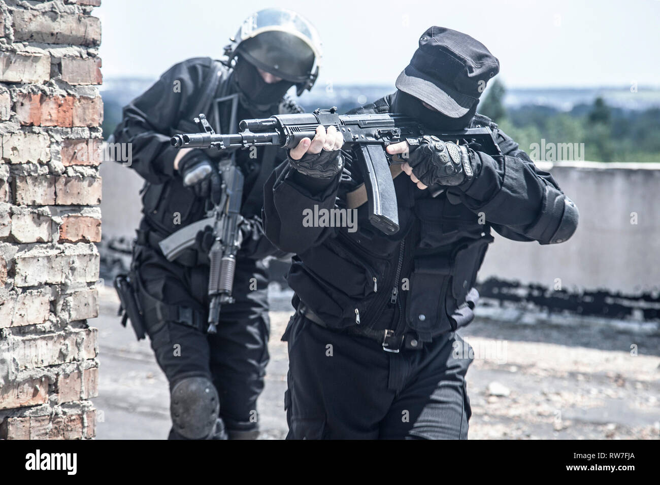 Two spec ops soldiers in black uniform in action Stock Photo - Alamy