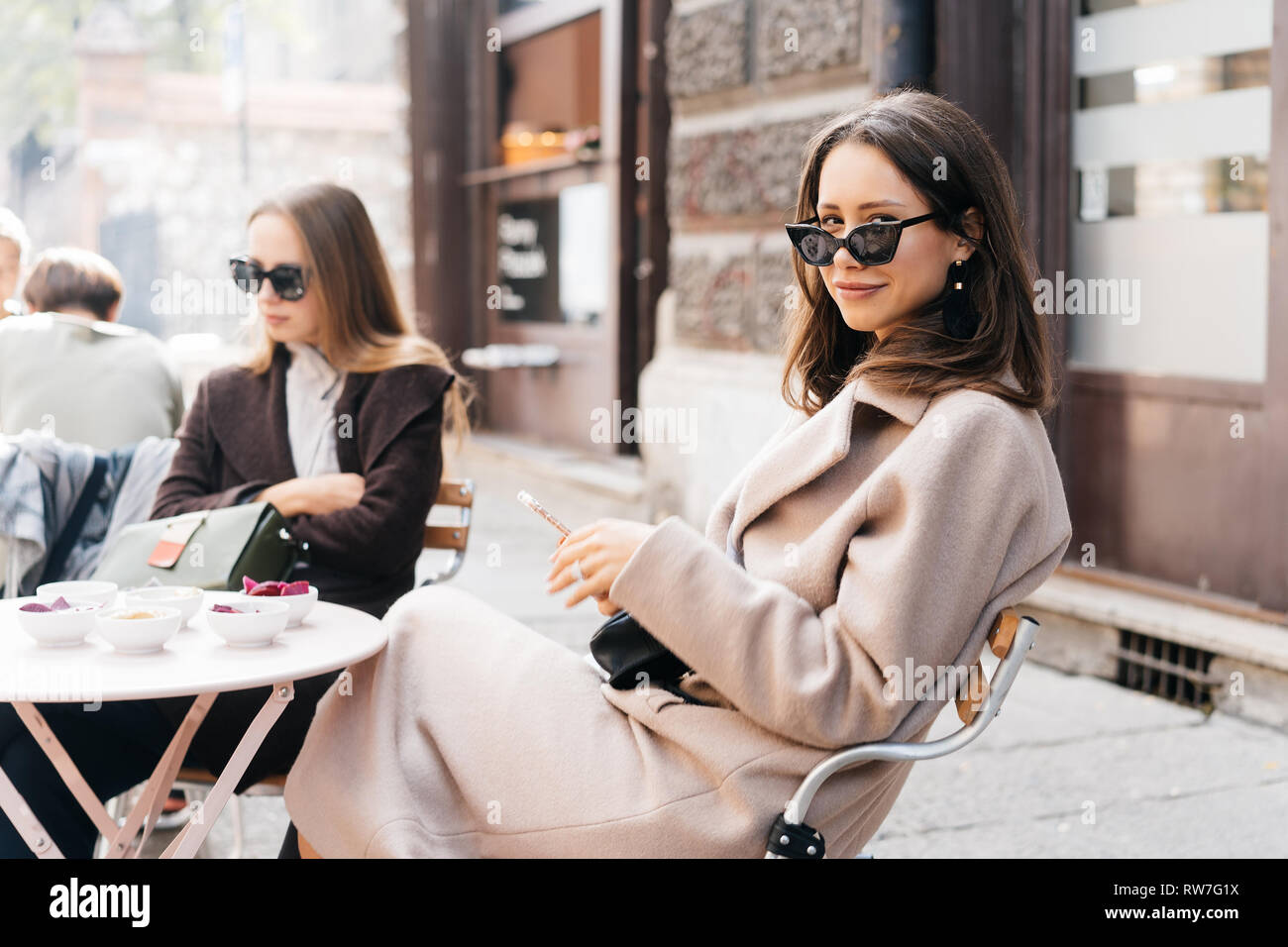 Young stylish woman posing in modern street cafe Stock Photo - Alamy