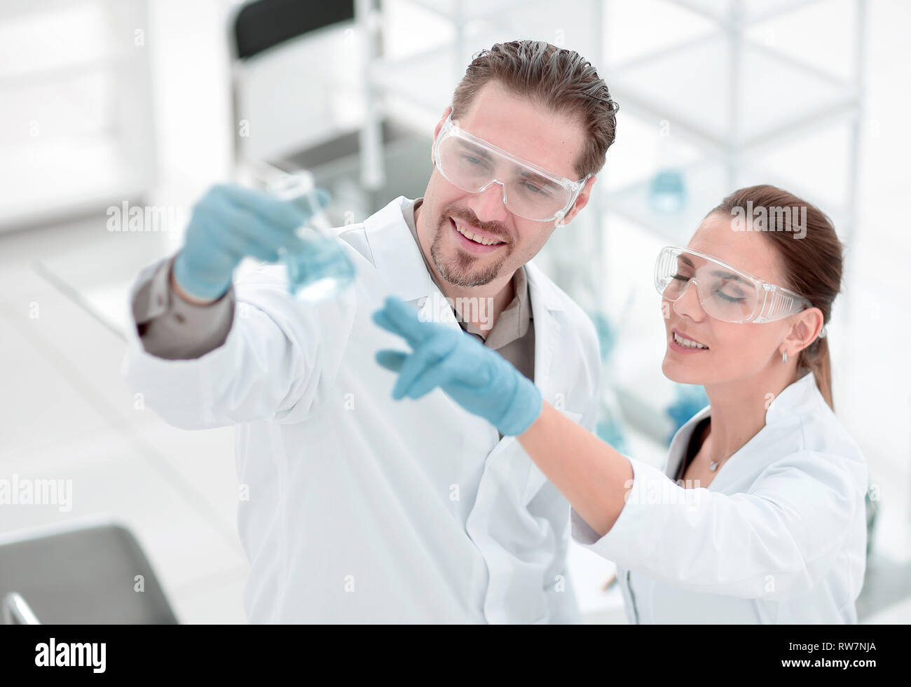 scientist and assistant look at the liquid in the flask Stock Photo - Alamy